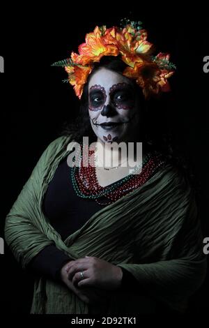 A woman disguised as Catrina poses in a field flowers on October 27 ...