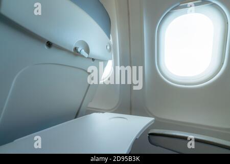 Plane window with white sunlight. Empty plastic airplane tray table at ...