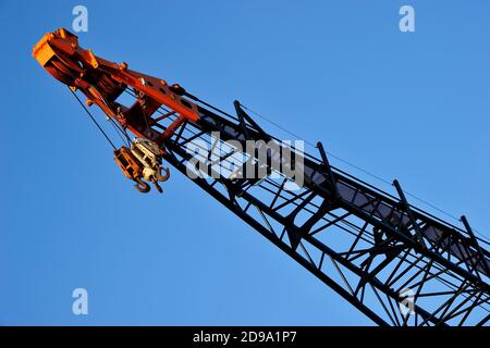 A orange crane boom with hooks on a blue sky background with clipping ...