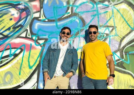 Friends having fun graffiti wall background Stock Photo - Alamy
