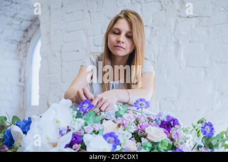 Florist workshop. Pretty woman making wreath from dandelions. Romantic ...
