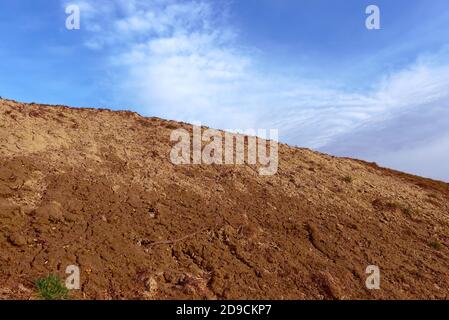 The slope of a clay hill against the backdrop of a beautiful blue sky ...