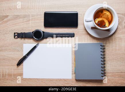 Smartphone and smartwatch next to a notebook and blank card on a wooden ...