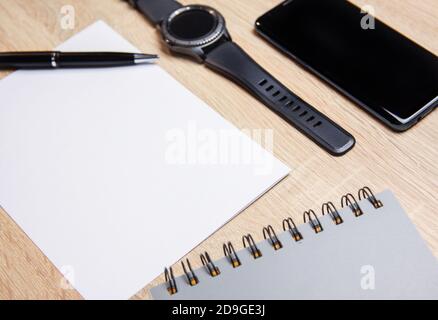 Smartphone and smartwatch next to a notebook and blank card on a wooden ...