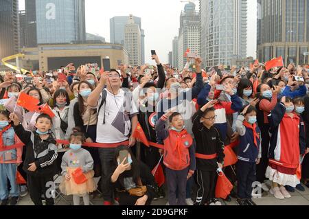 People wave Chinese flags while watching the Chinese flag raising ...