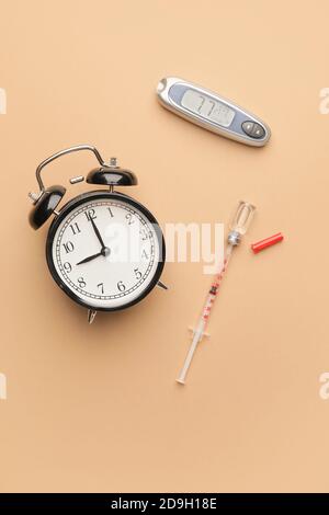 Glucometer with alarm clock, syringe and bottle of insulin on color ...