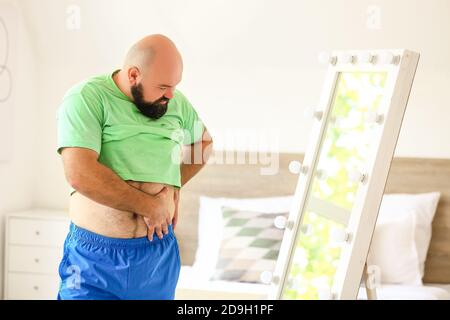 Obese man looking at his mirror reflection, overweight problem and ...