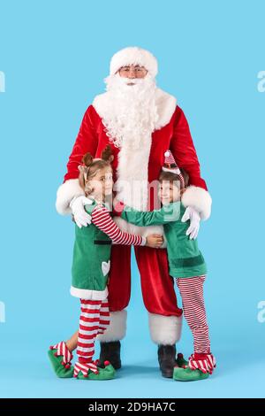 Cute little elves with Santa Claus on color background Stock Photo - Alamy