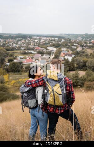 Back view of man with backpack hugging african american girlfriend ...