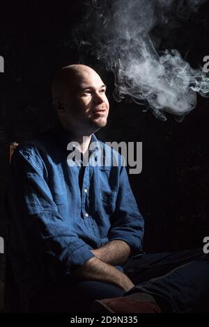 Matured bold man smoking, portrait on black background Stock Photo - Alamy