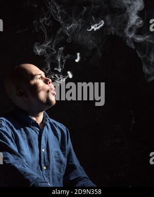 Matured bold man smoking, portrait on black background Stock Photo - Alamy