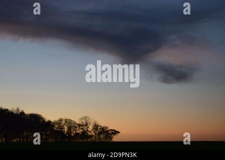 Cirrus type clouds tinged with colour from the setting sun highlighting ...