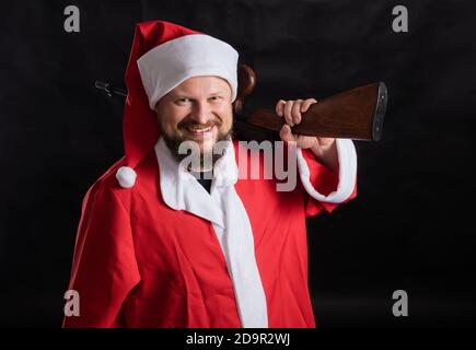 Cheerful Santa with machine gun studio portrait on black background ...