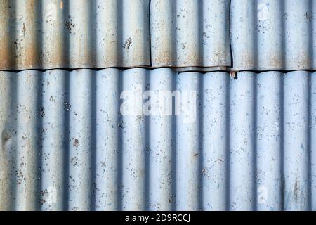Weathered corrugated metal wall with rust and aged paint creating an ...