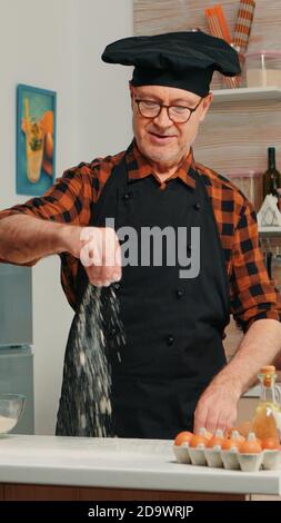 Experienced baker spreading flour in home kitchen for food preparation ...