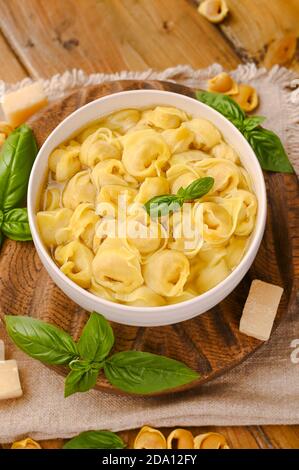 Tortellini mignon on a wooden board and parmesan. Specialties of the ...