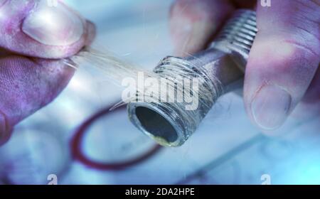 Plumber putting hemp fibers on a thread, closeup Stock Photo - Alamy
