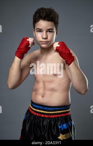 Young kickboxer with hands wrapped training in shadow boxing against ...