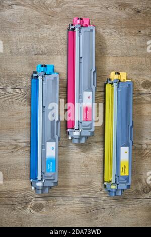 Three used toner cartridges in a color laser printer stacked on gray ...