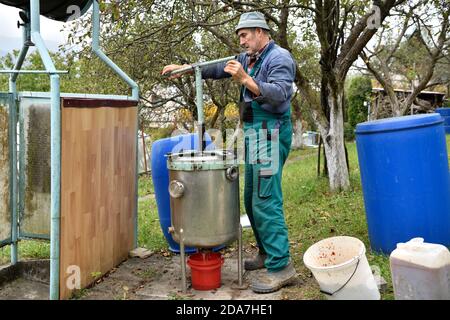 The fruit grower presses crushed apples for fruit juice Stock Photo - Alamy