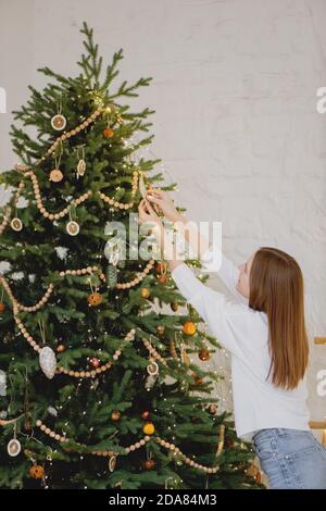 Smiling young beautiful woman decorating Christmas tree Stock Photo - Alamy