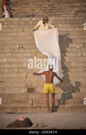 Varanasi, India, January 2008. Two people drying a sheet on the stairs ...