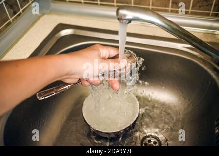 hand washing spoon under the tap in the sink. the plate is blurred ...
