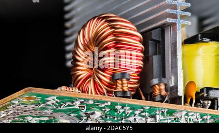 Toroidal electronic inductors soldered on circuit board. Copper wire ...