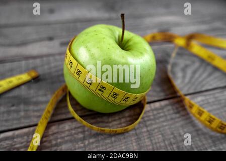 Closeup shot of a green apple measured the meter on a wooden background ...