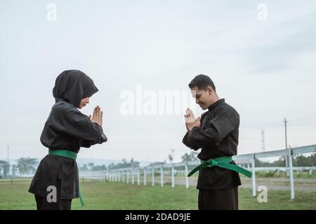 two fighters in pencak silat Hitam uniform fight in low stance and side ...
