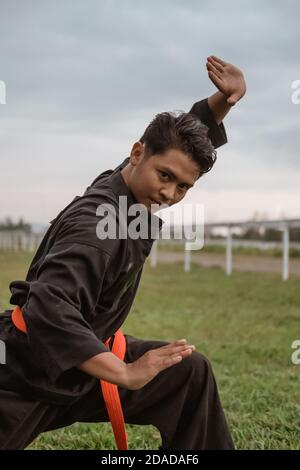 Asian men wearing pencak silat uniforms with red belts do dodging ...