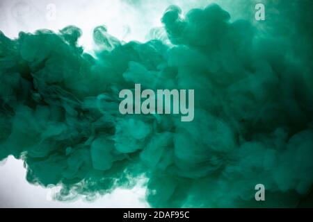 Green smoke bomb exploding against white background Stock Photo - Alamy