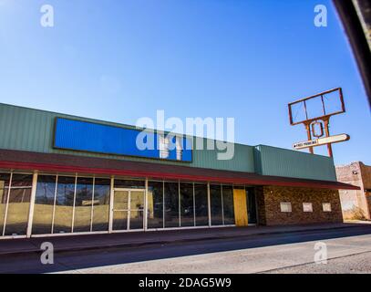 Boarded windows and a broken neon sign atop an abandoned brick building ...