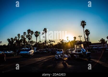 West Coast sunset over a parking lot of cars, palm trees, and the ...
