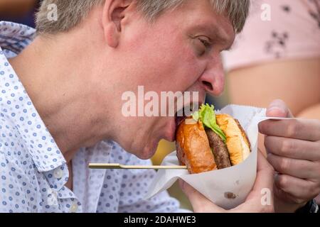 Hungry man eating yummy burger Stock Photo - Alamy