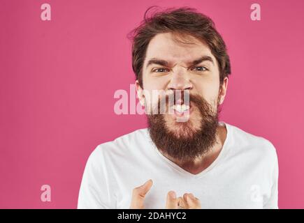 An angry man with a bushy beard bared his teeth against a pink ...