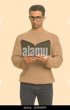 Young handsome Iranian man reading book while holding coffee cup Stock ...