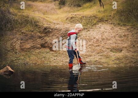 Blonde child trying to catch some fish with a hand net Stock Photo - Alamy