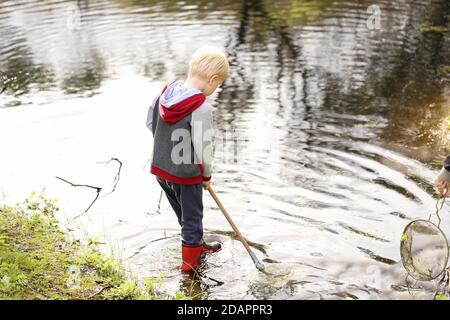 Blonde child trying to catch some fish with a hand net Stock Photo - Alamy