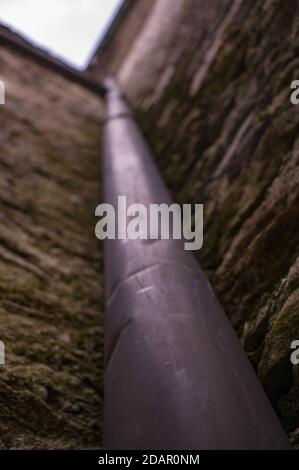Vertical shot of a pipe going up on the old building exterior wall ...