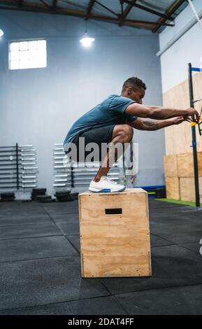 Strong man doing a box jump exercise at workout gym. Male athlete using ...