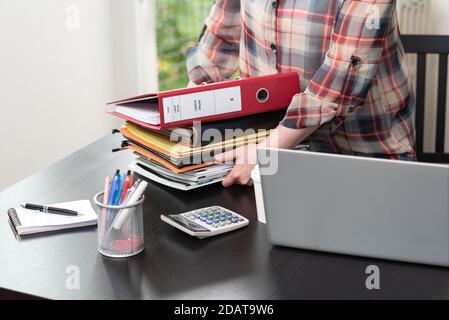 Businesswoman putting a stack of binders and folders on her desk; light ...