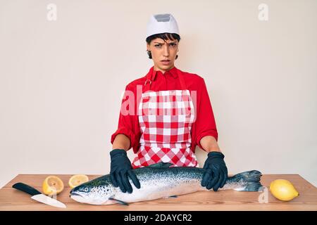 Beautiful brunettte woman fishmonger cooking fresh raw salmon smiling ...