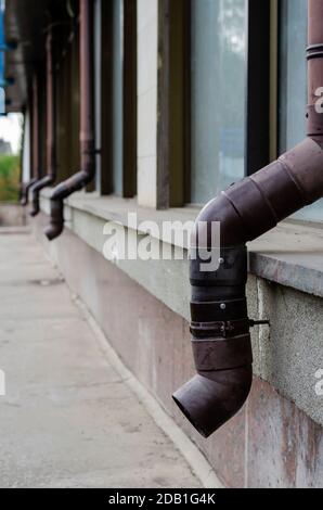 Facade of building with attached brown gutters. Row of plastic rain ...