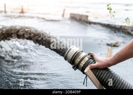 Engeneer hold pipe of power pump machine pouring mud sludge waste water ...