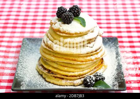 Pancakes with blackberries and icing sugar on a green natural ...