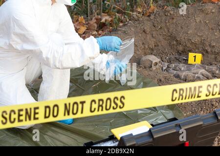 Forensic science specialist gathering evidence at a crime scene. Exhumation site Stock Photo - Alamy