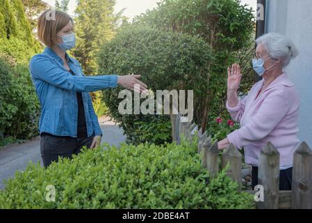 Senior woman with face mask shows safety distance to neighbor woman ...