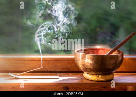 Singing bowl and incense stick on a light wooden background. Yoga ...