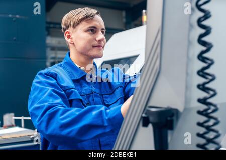 Young male worker programming lathe machine in factory Stock Photo - Alamy
